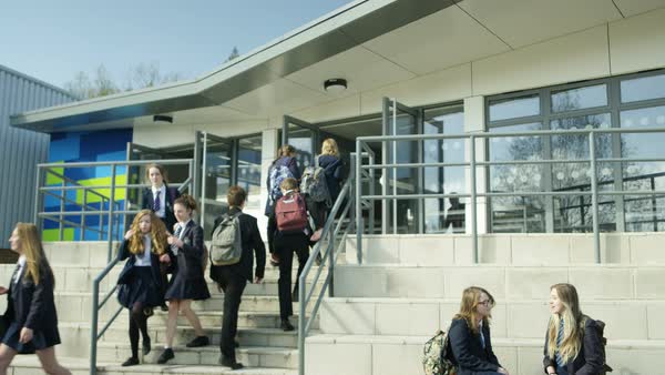 Young students walking into school building at the beginning of the day ...
