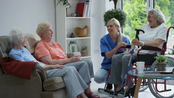Caring nurse taking care of and talking to elderly residents in a ...