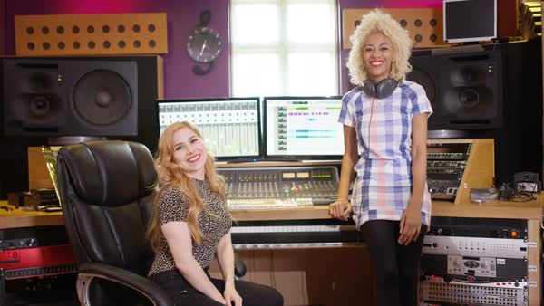 Portrait of two young women in recording studio working at the mixing ...