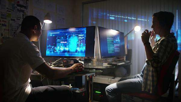 Young creative computer design team working together in dark office ...