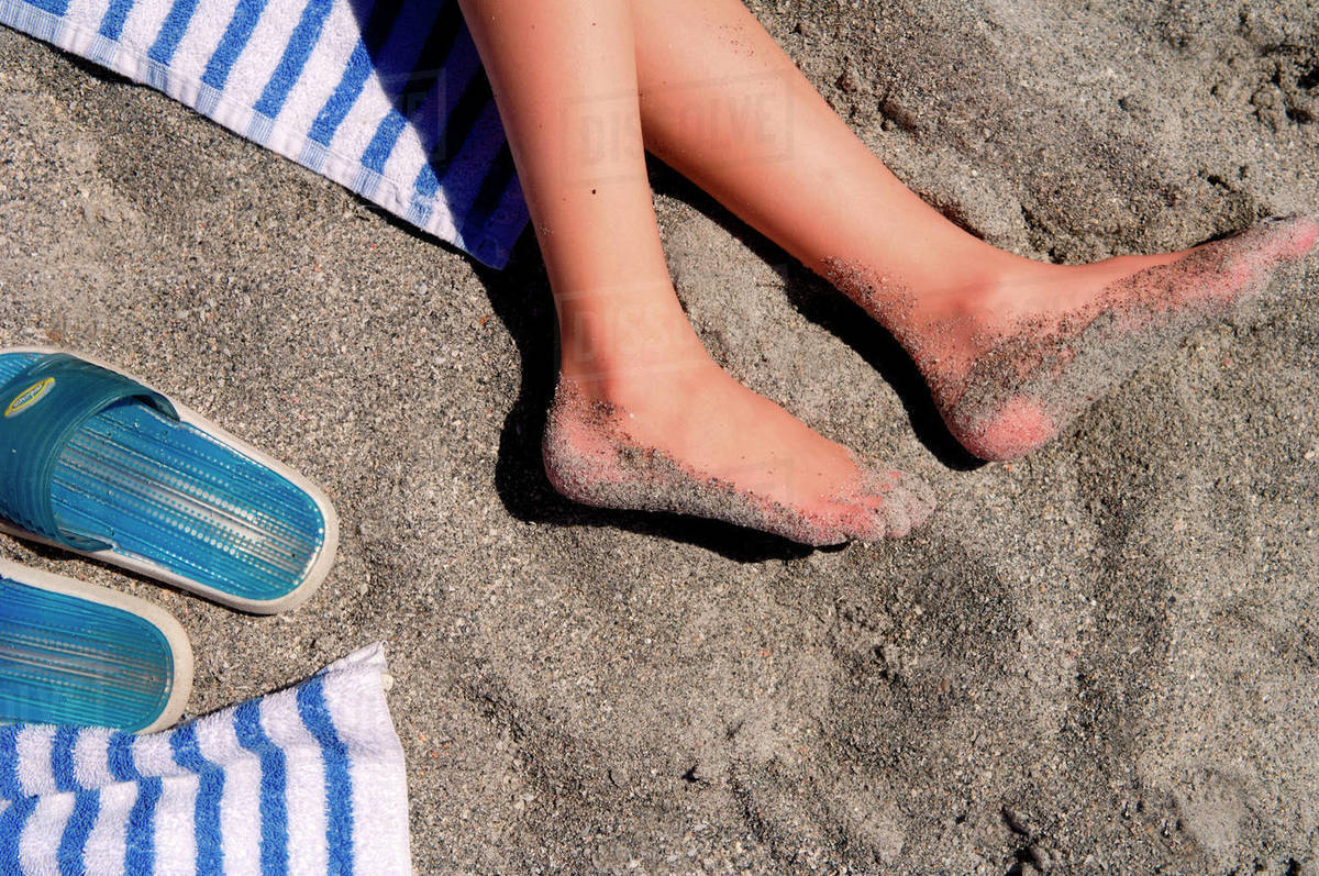 Someone Lays With Feet In The Sand On The Beach. - Stock Photo - Dissolve