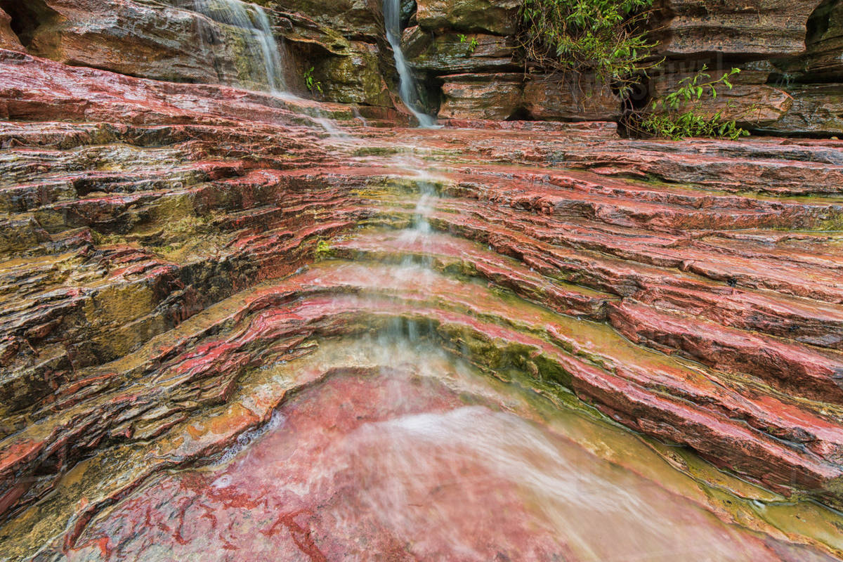 Water flows over a very colourful waterfall in the heart of Toro Toro ...