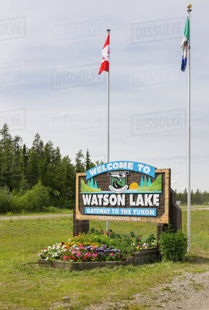 A Welcome to Watson Lake sign with flags in the background, Yukon ...