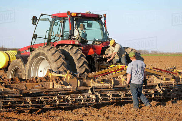 Agriculture - Three farmers work to set up a secondary tillage ...