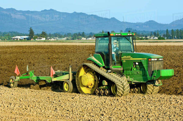 Agriculture - A John Deere tracked tractor pulling a reversible plow ...