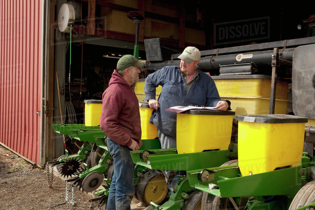 Agriculture - Two farmers in a farm equipment shop with a planter ...