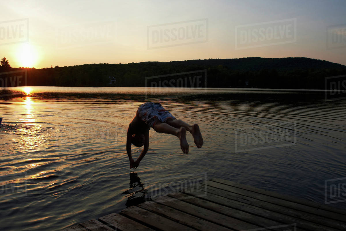 Boy diving into a lake at sunset; Lac des Neiges, Quebec, Canada ...