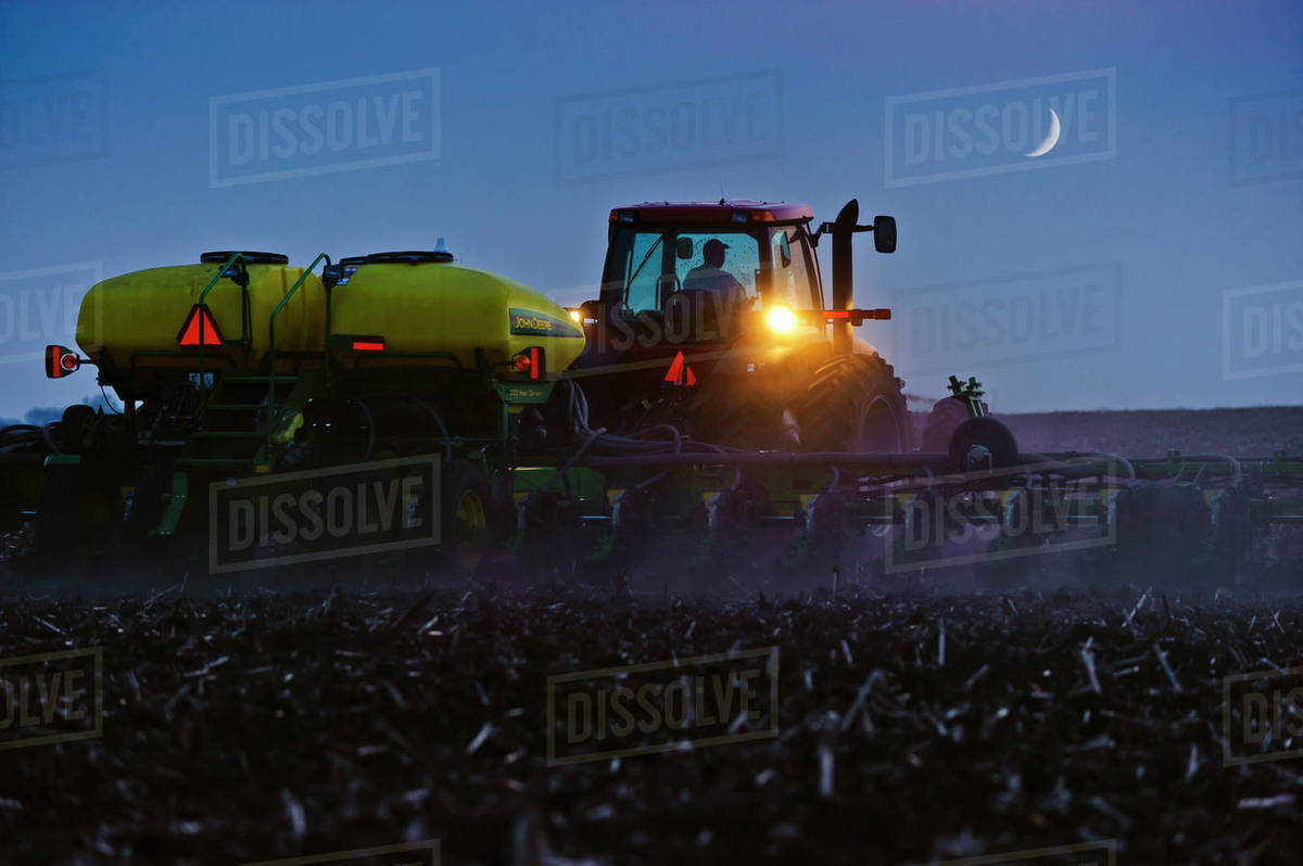 Agriculture - A farmer plants a soybean crop at night with a crescent ...