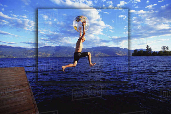 Boy Jumping Into Lake With Globe Beach Ball - Stock Photo - Dissolve