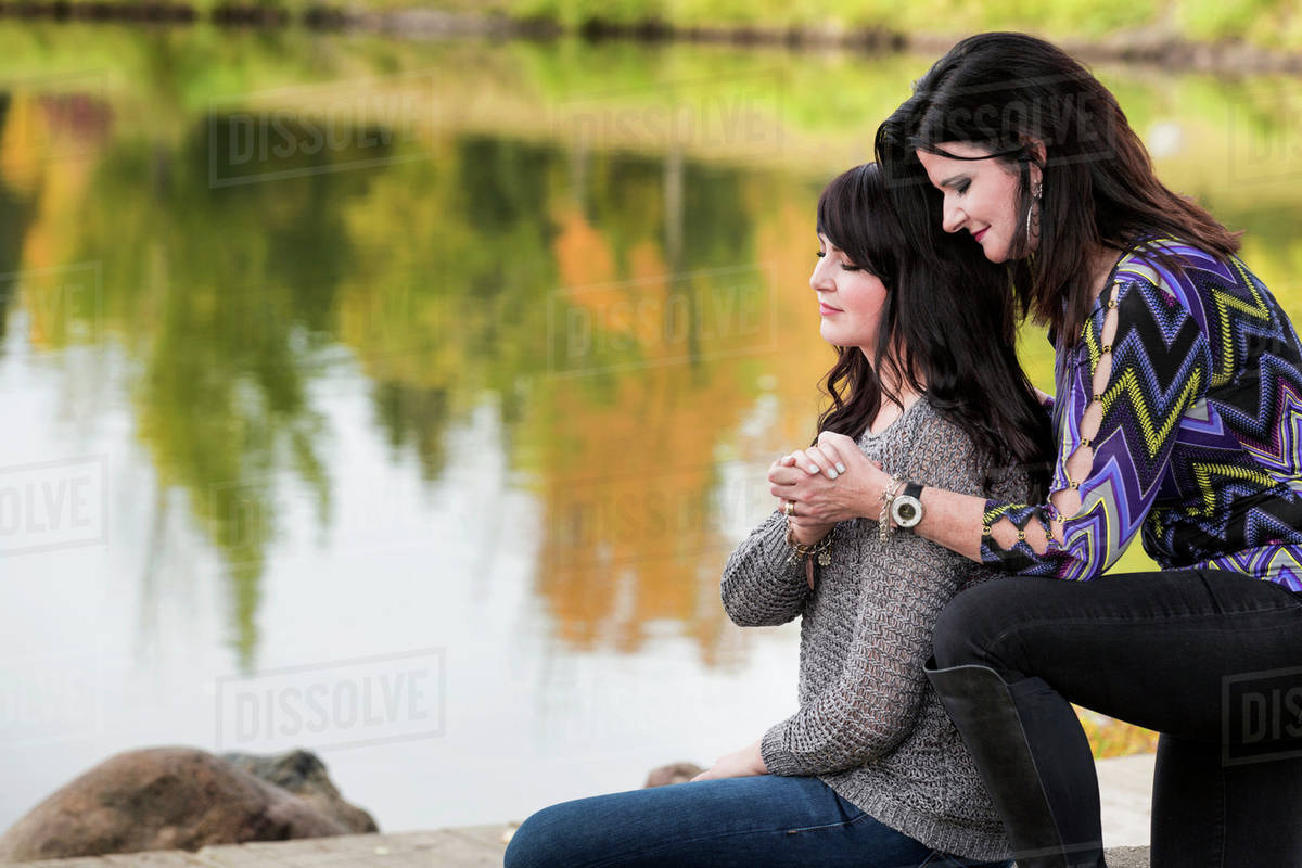 Mother and daughter praying together in a city park in autumn; St ...