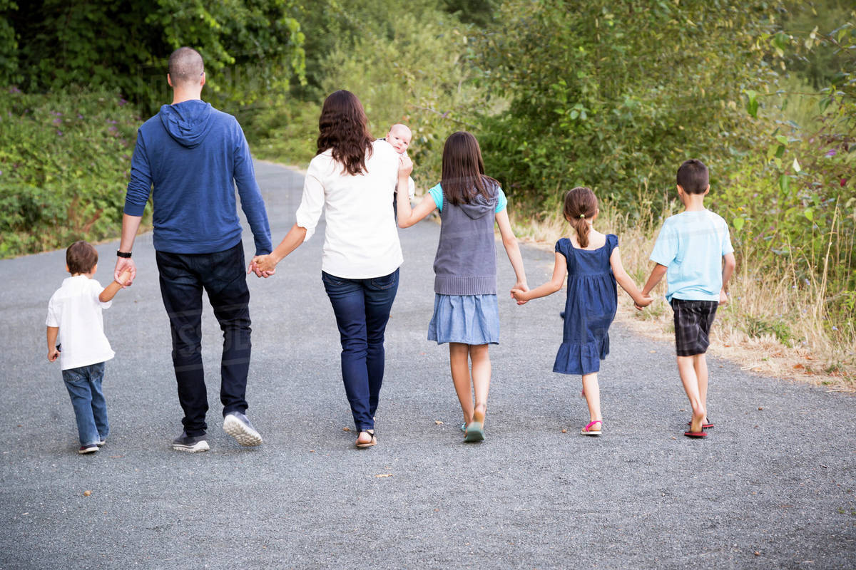 Portrait of a family with five children walking hand in hand down a ...