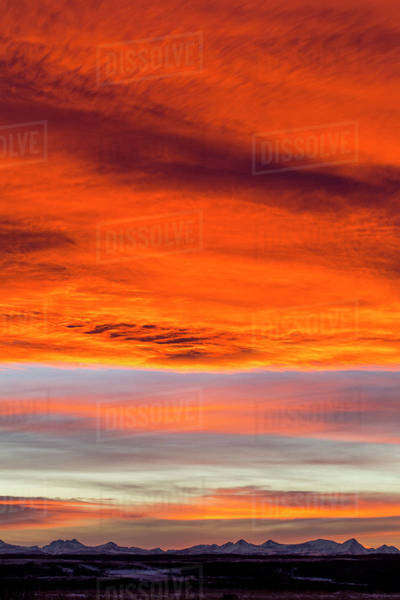 Dramatic fiery sunset with orange and red clouds and mountains in the ...