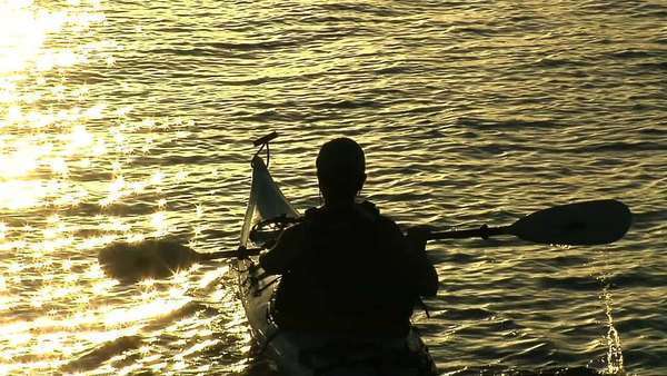 Kayaker paddles away from as sunset reflects off water - Stock Video ...