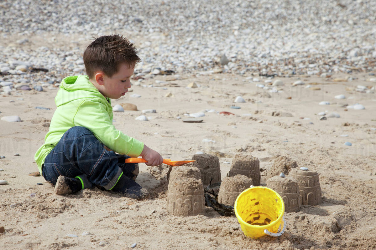 A young boy plays on the beach building a sand castle; South Shields ...