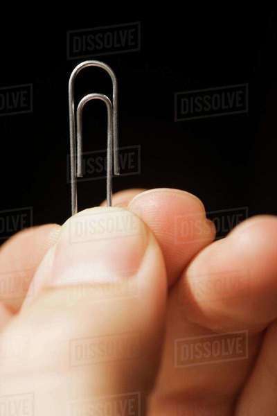 Person Holding Up A Paperclip - Stock Photo - Dissolve