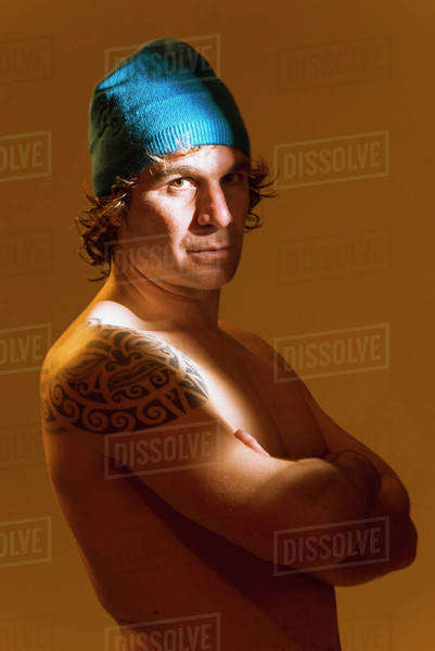 Portrait of a shirtless man with a large tattoo on his shoulder wearing ...