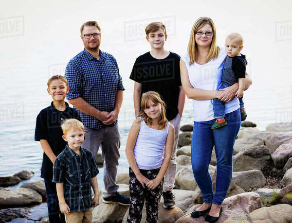 Outdoor portrait of a family with five young children standing on rocks ...