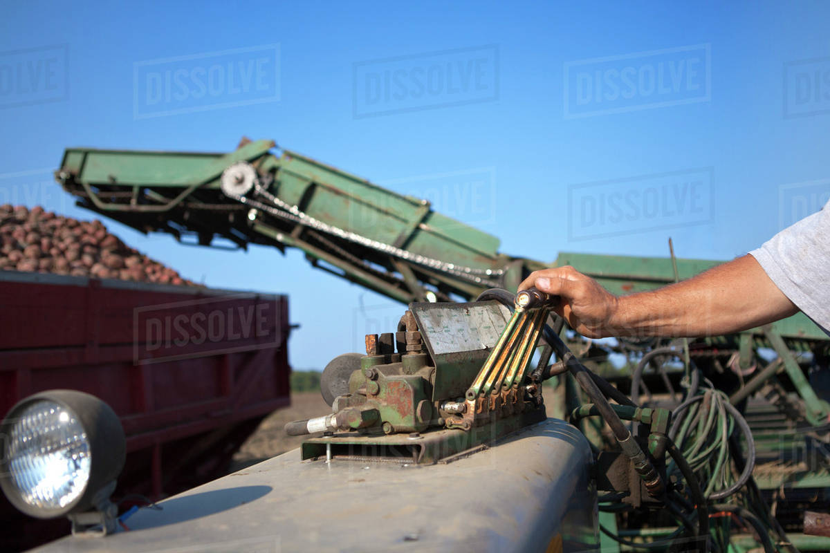 Agriculture - A farmers hand operates levers on the harvester during ...