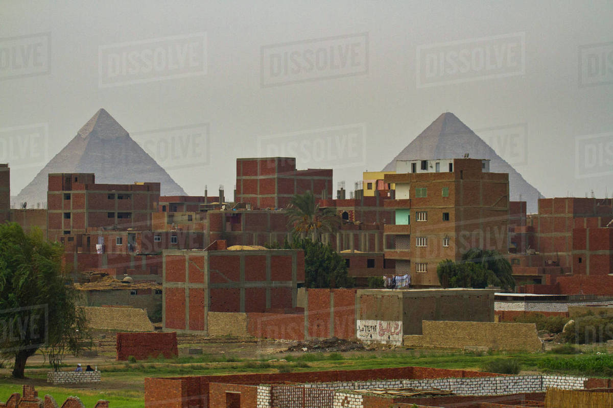 Pyramids behind the town of Giza; Giza, Egypt - Stock Photo - Dissolve