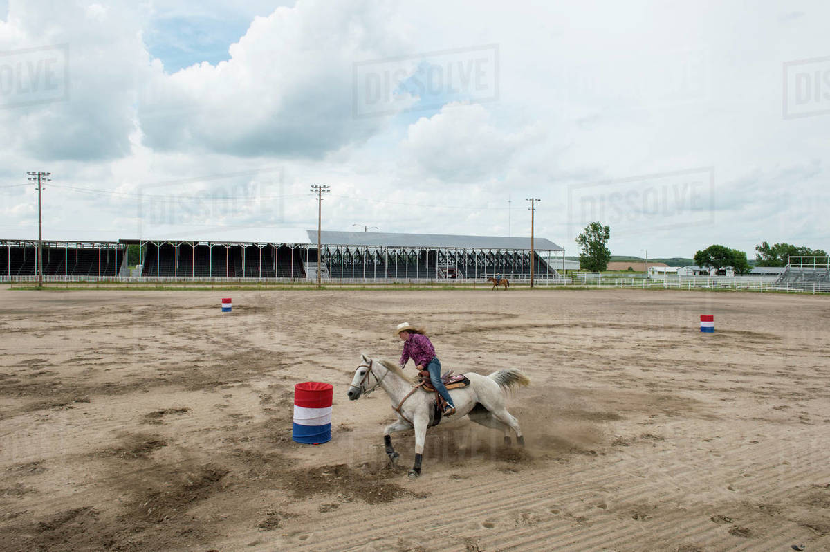 Teenage girl practices barrel racing with her horse; Burwell, Nebraska ...