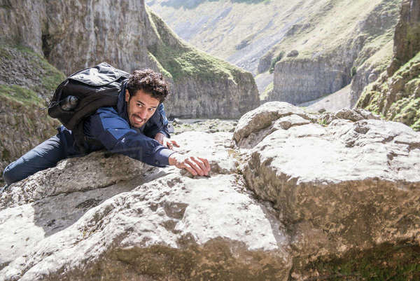 A mountaineer climbing over rocks in rugged terrain. - Royalty-free ...