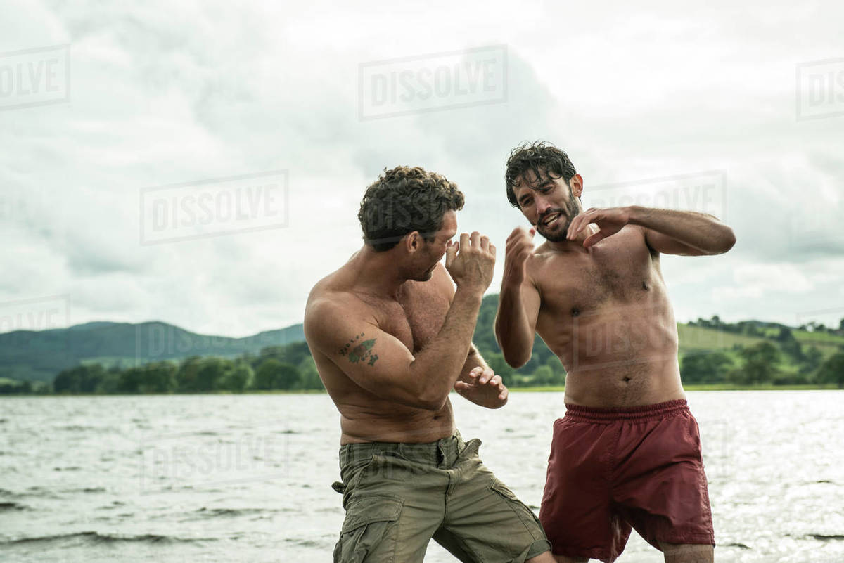 Two bare chested man shadow boxing in the shallow water of Bala Lake in ...