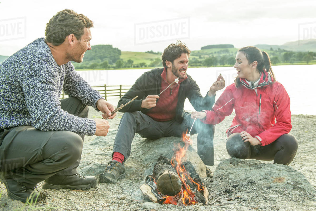 Three friends relax around a campfire on the shore of Bala Lake in ...