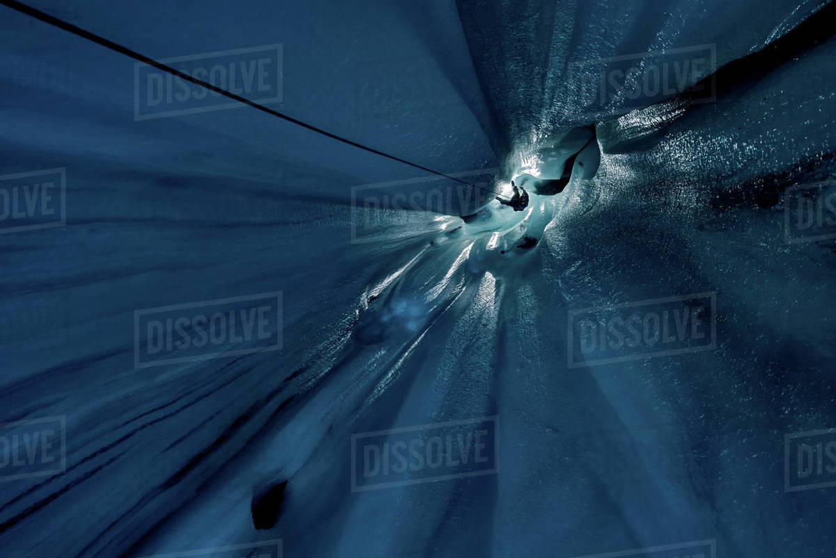 A cave explorer hangs on a rope inside a moulin on the Aletsch Glacier ...