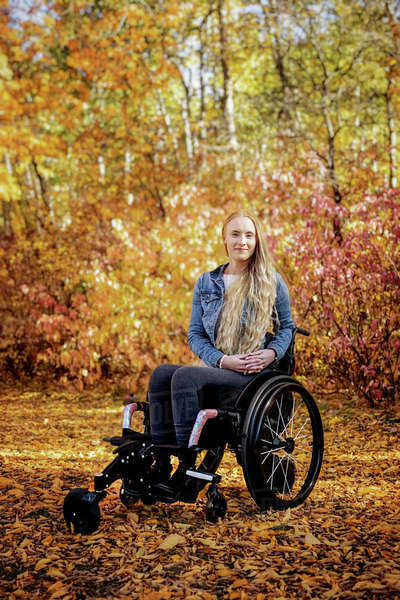 A young paraplegic woman in her wheelchair in a park on a beautiful ...
