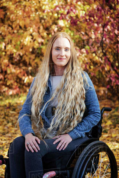 A young paraplegic woman in her wheelchair in a park on a beautiful ...
