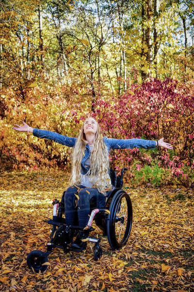 A young paraplegic woman in her wheelchair in a park on a beautiful ...