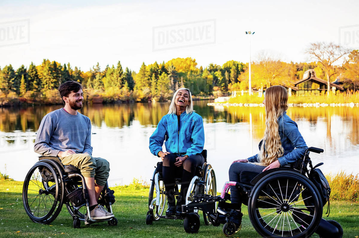 Group of three young paraplegics in their wheelchairs visiting together ...