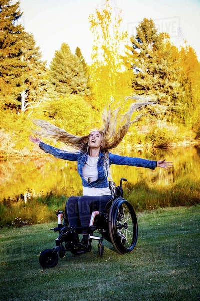 Young paraplegic woman in her wheelchair in a park on a beautiful fall ...