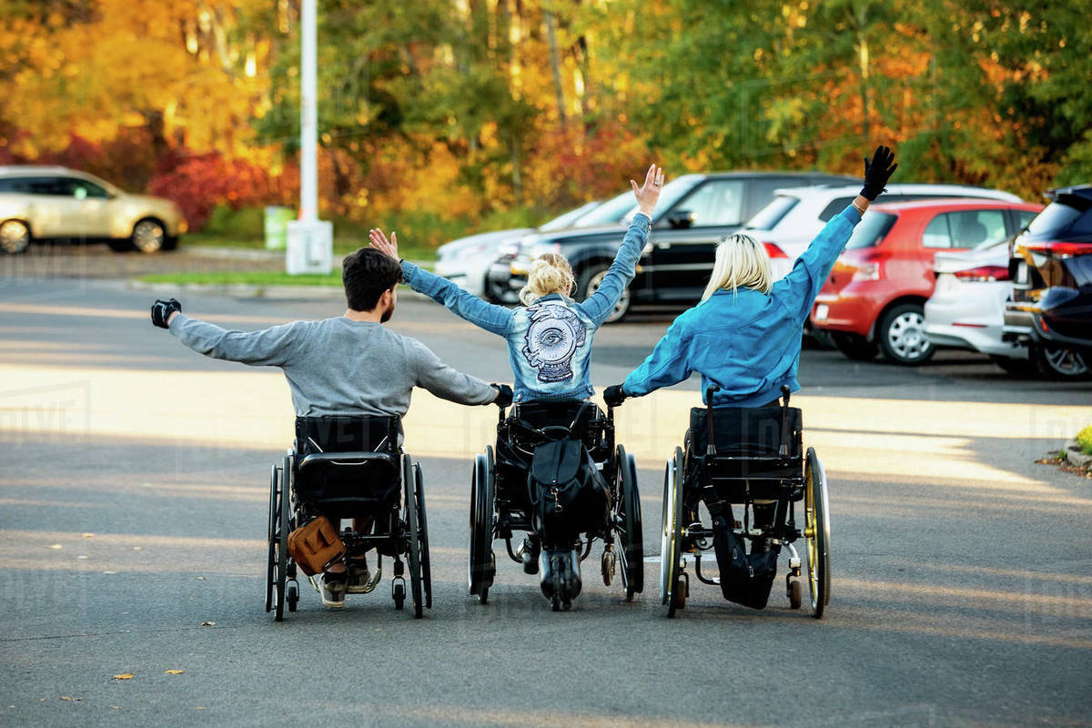 Three young paraplegics in their wheelchairs going through a parking ...