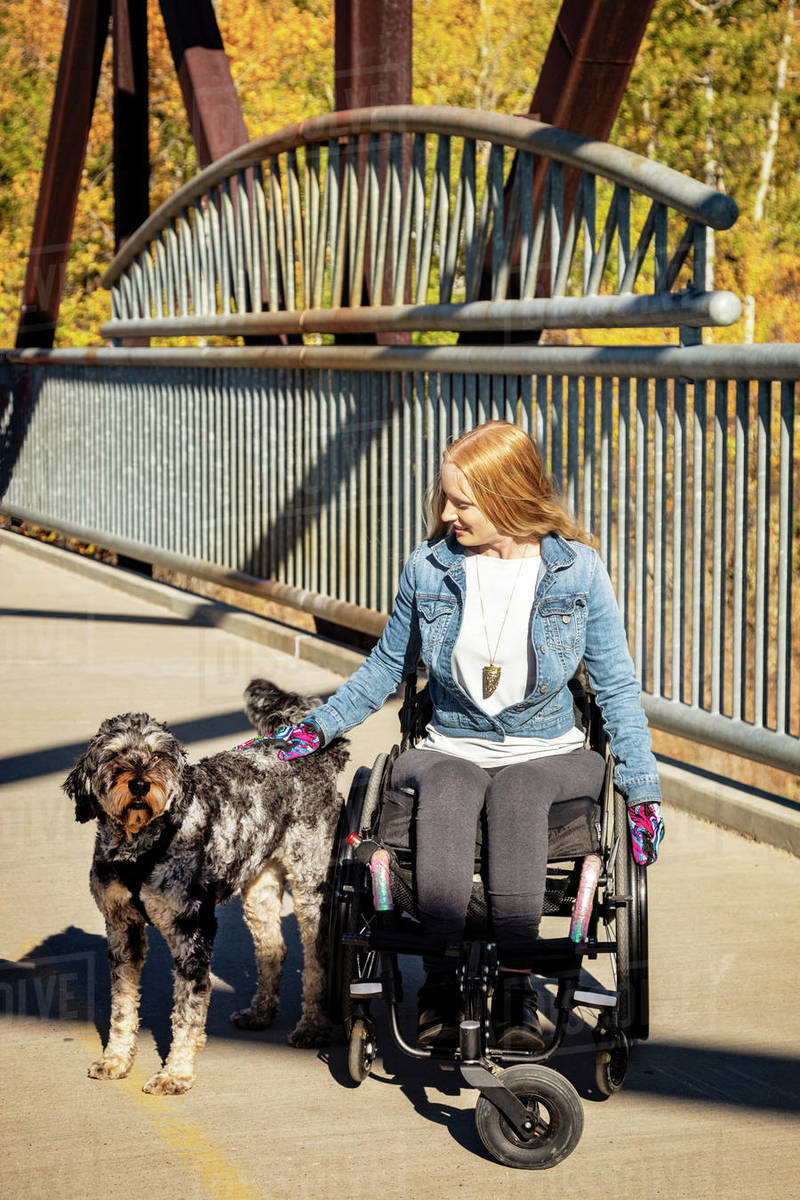 Young paraplegic woman in her wheelchair in a park on a beautiful fall ...