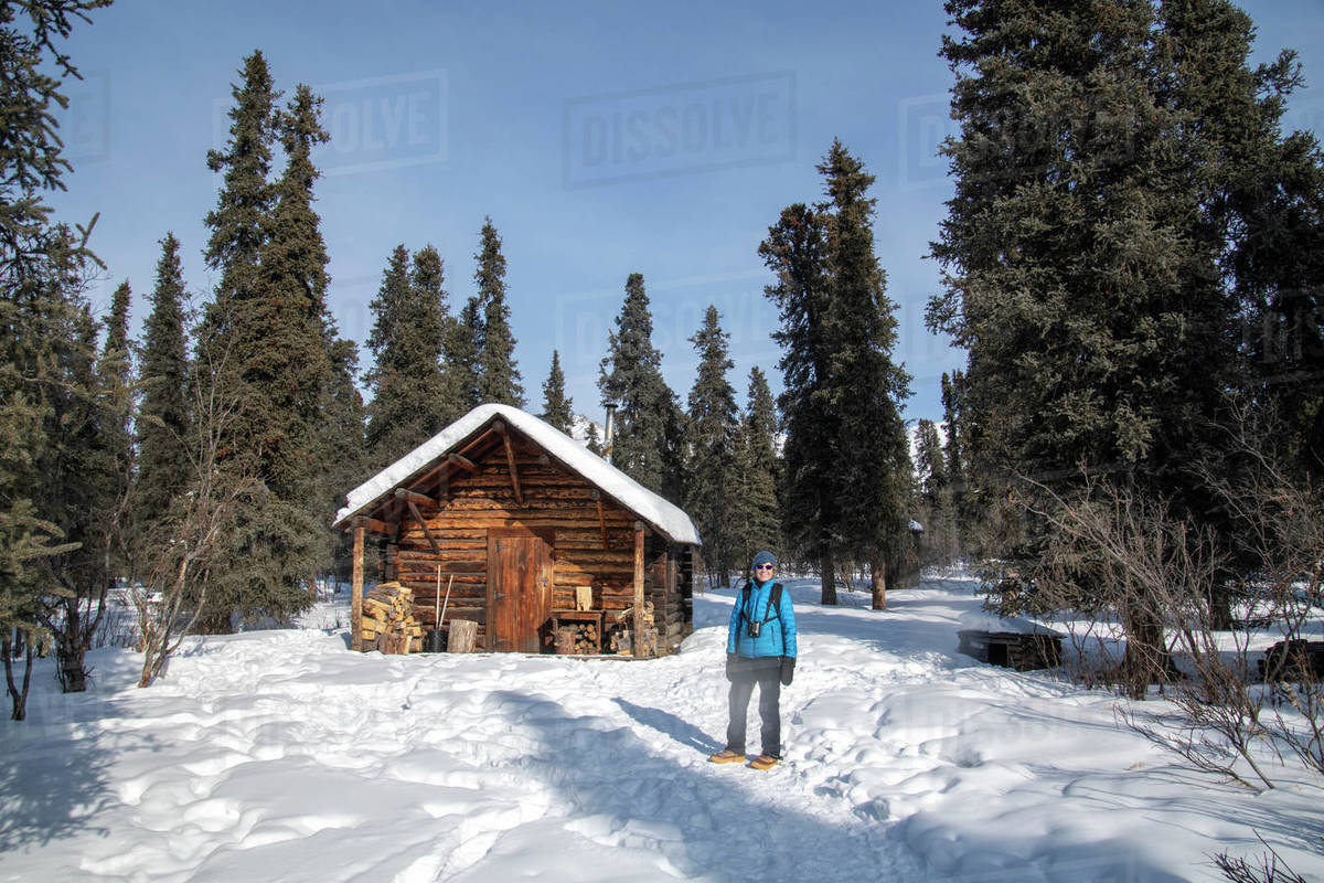 Woman tourist at the historic Savage Cabin during winter; Denali ...