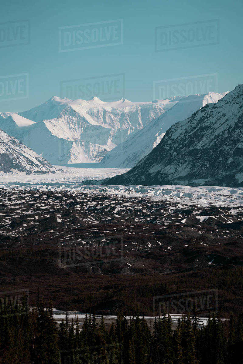 The Matanuska Glacier flows with the towering snow covered peaks of the ...