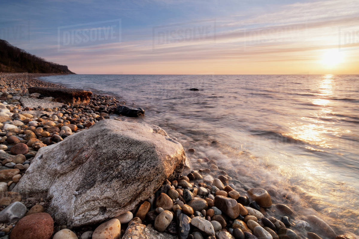 Sunrise kisses rock and water as it rises on the shores of Lake ...