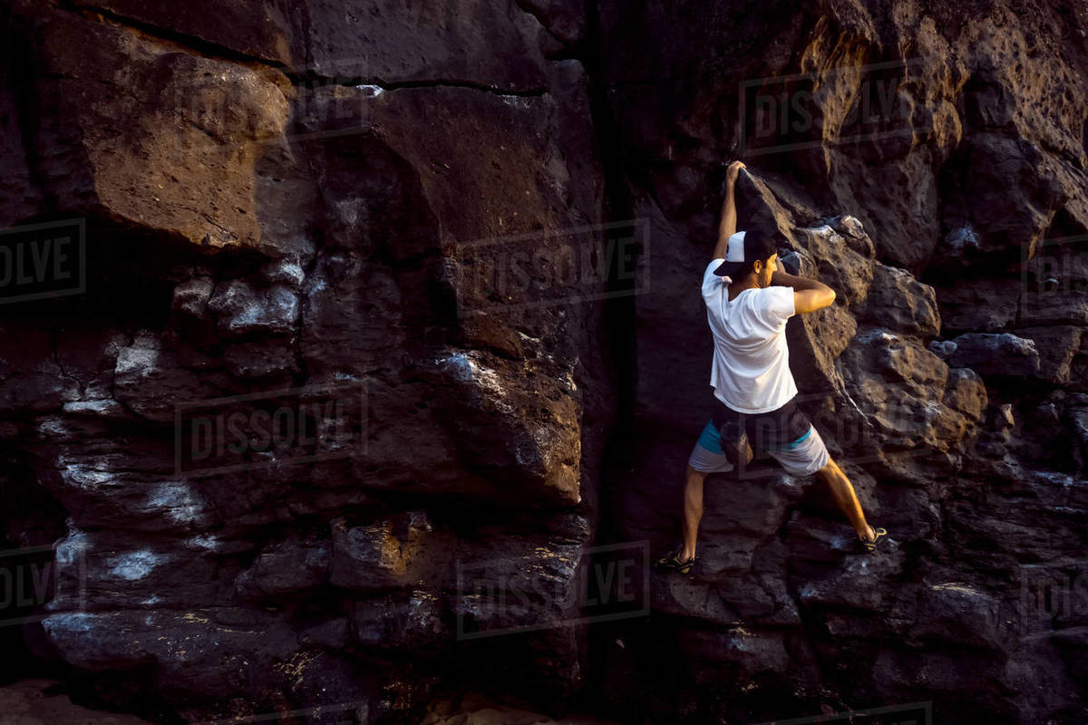 A man bouldering on the beach in Oahu. - Stock Photo - Dissolve