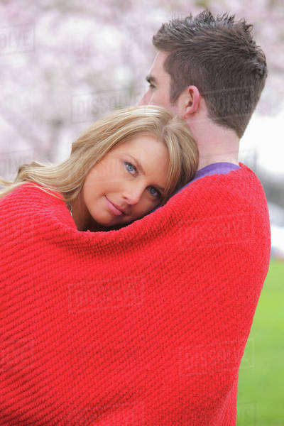 Couple Cuddled Up In A Red Blanket With Young Woman Looking At The ...