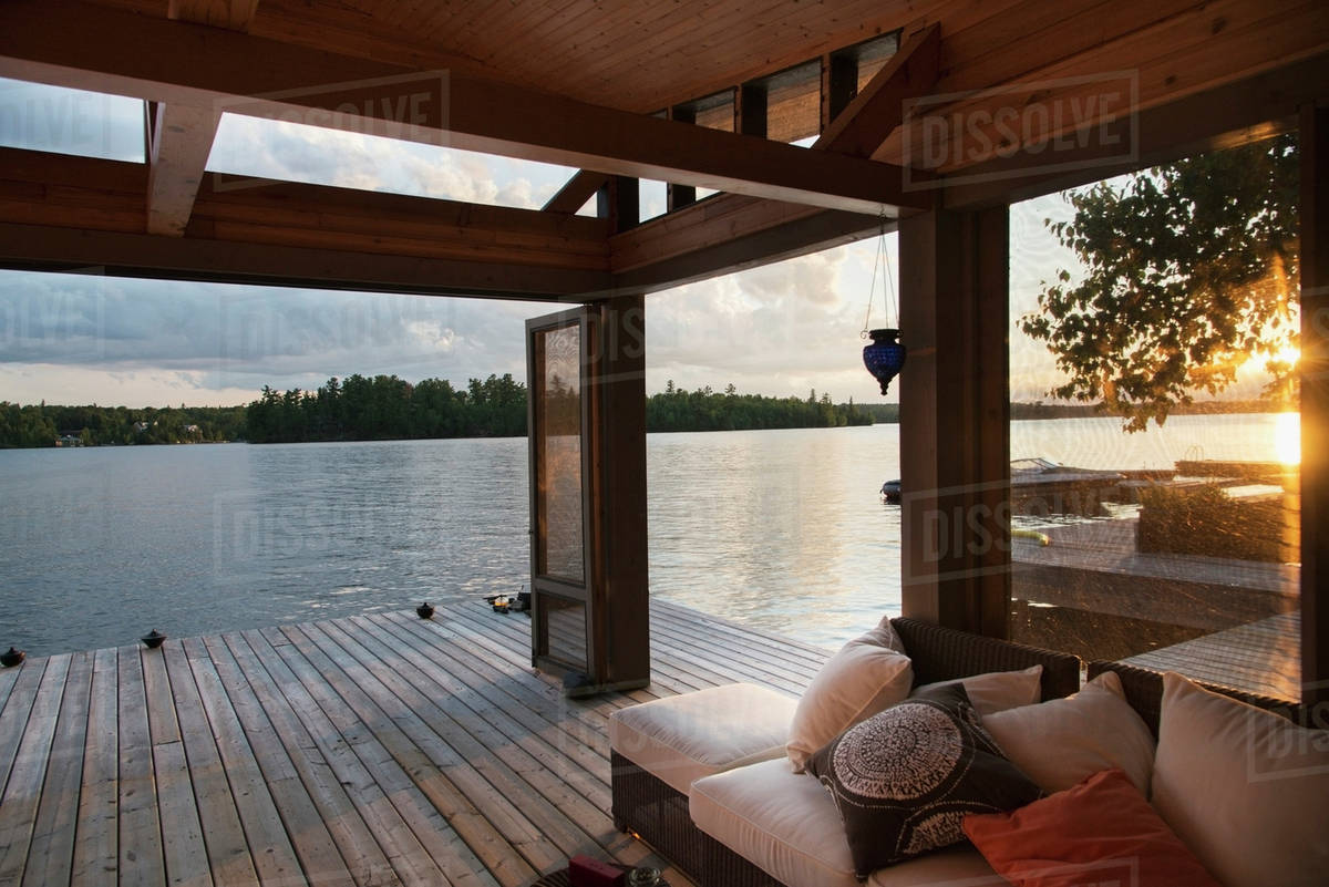 Covered patio on a wooden deck on the water's edge at sunset;Lake of ...