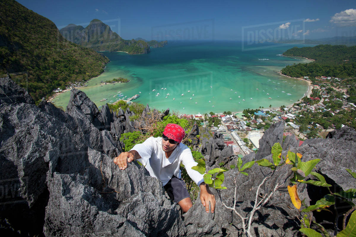 A Man Rock Climbs On Top Of Sharp Limestone Spires Overlooking The ...