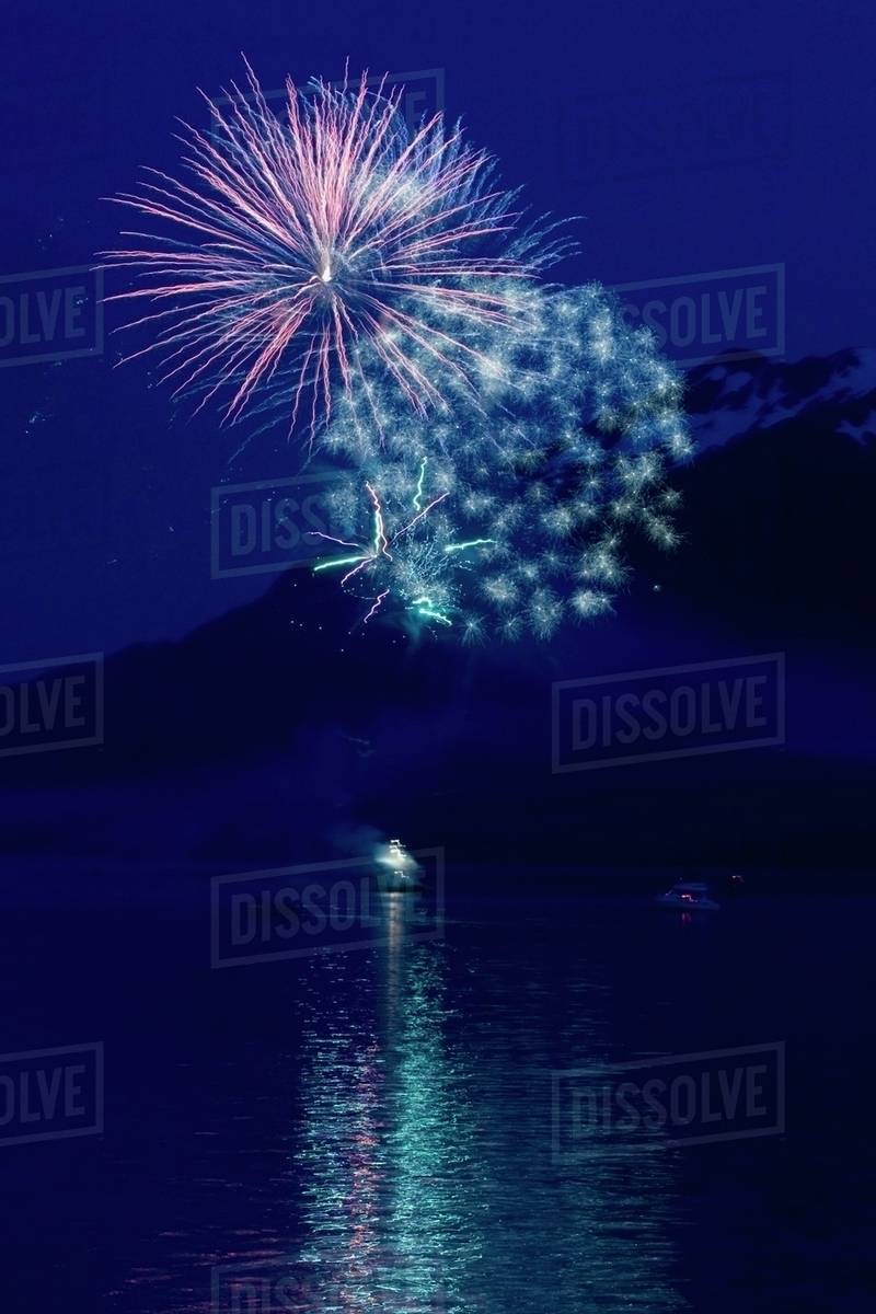 Fireworks Over The Water With A Mountain In The Background - Stock ...