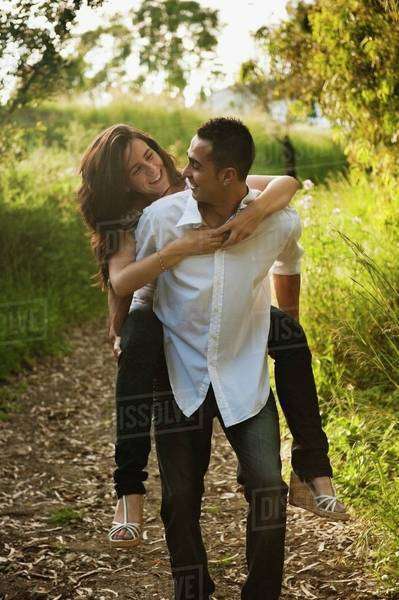 A Man With A Woman Riding On His Back On A Path; Benalmadena Costa ...