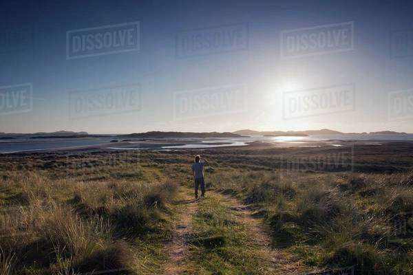 Man Viewing Sunset And Scenery From Hill - Stock Photo - Dissolve
