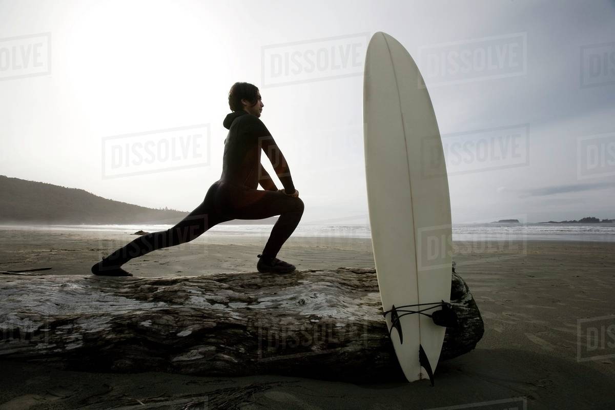 Surfer Stretching On Beach - Stock Photo - Dissolve