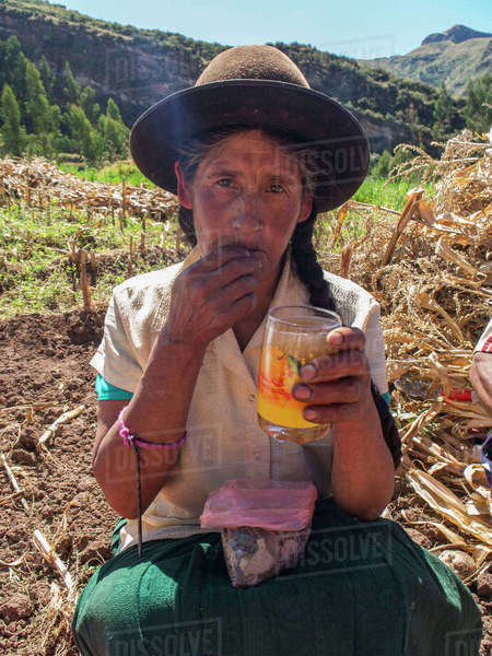 A Quechua farmer drinks chicha, a fermented corn drink and chews on ...