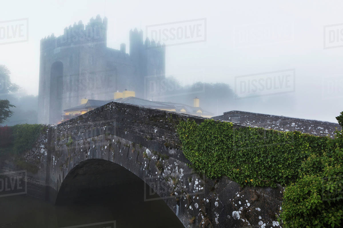Old stone bridge with castle in the background and fog; Bunratty ...