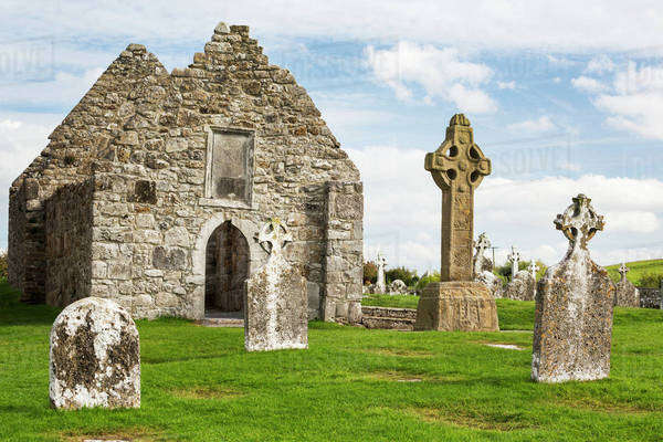 Ancient stone roofless church with celtic crosses in a grassy field ...