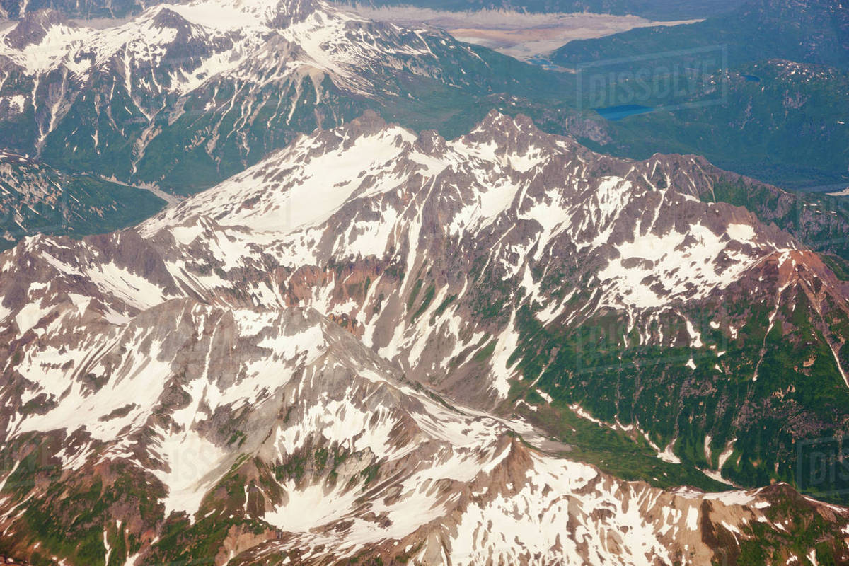 Aerial view of snow-covered mountains and bare rock peaks of the ...